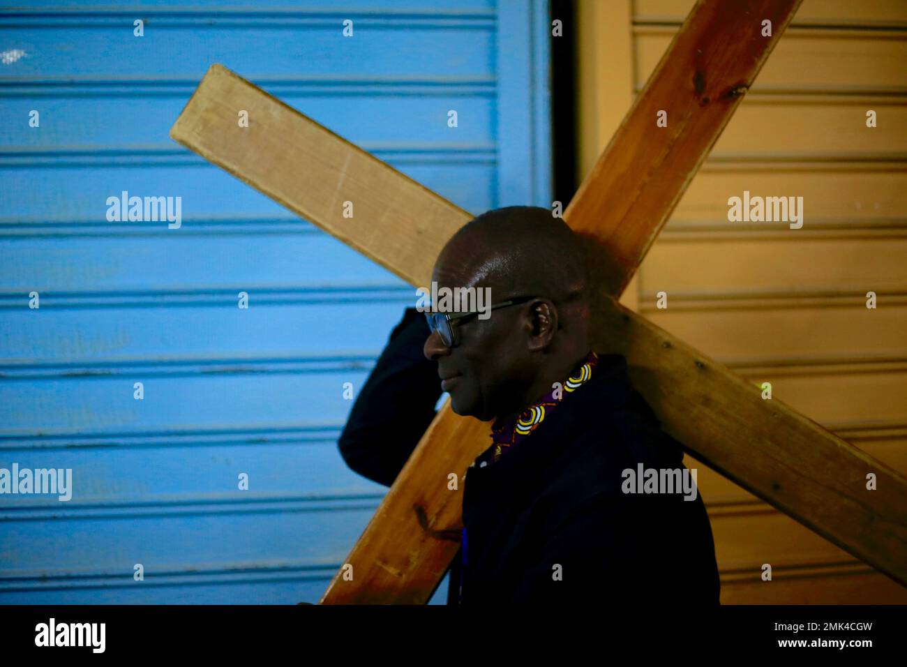 A Christian worshiper carries a cross walk along the Via Dolorosa ...