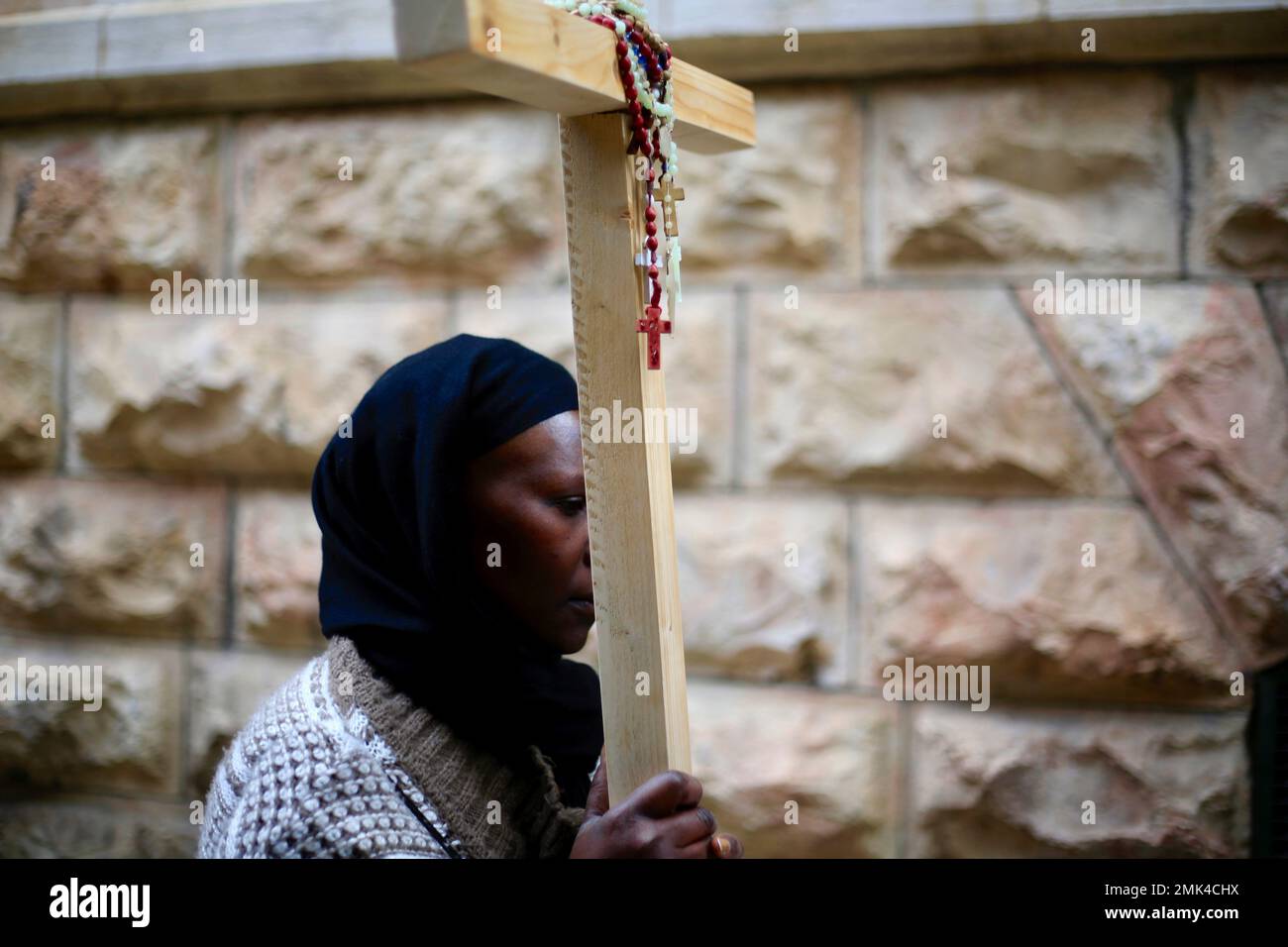 A Christian worshiper carries a cross walk along the Via Dolorosa ...