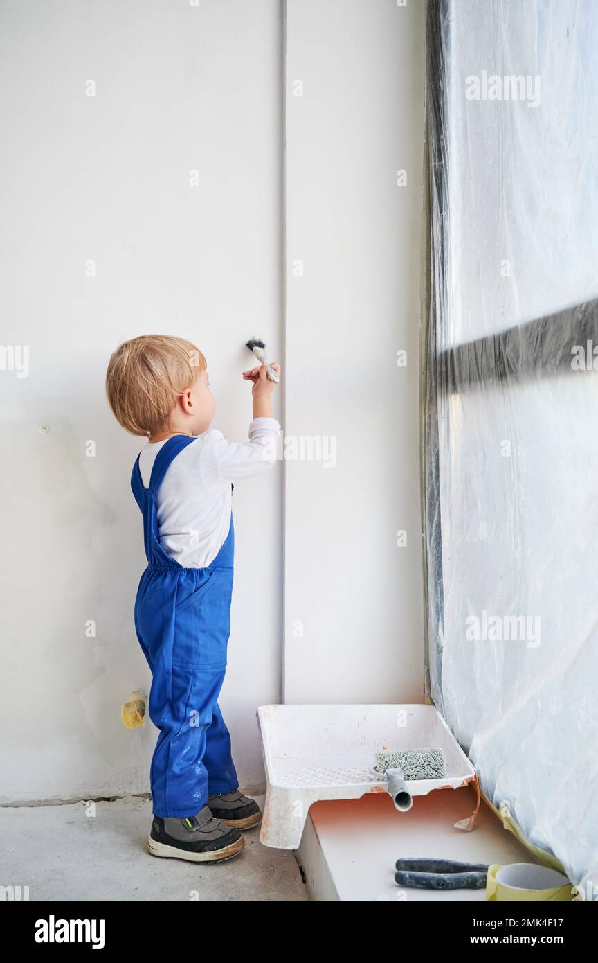 Full length of little boy construction worker standing by the window ...