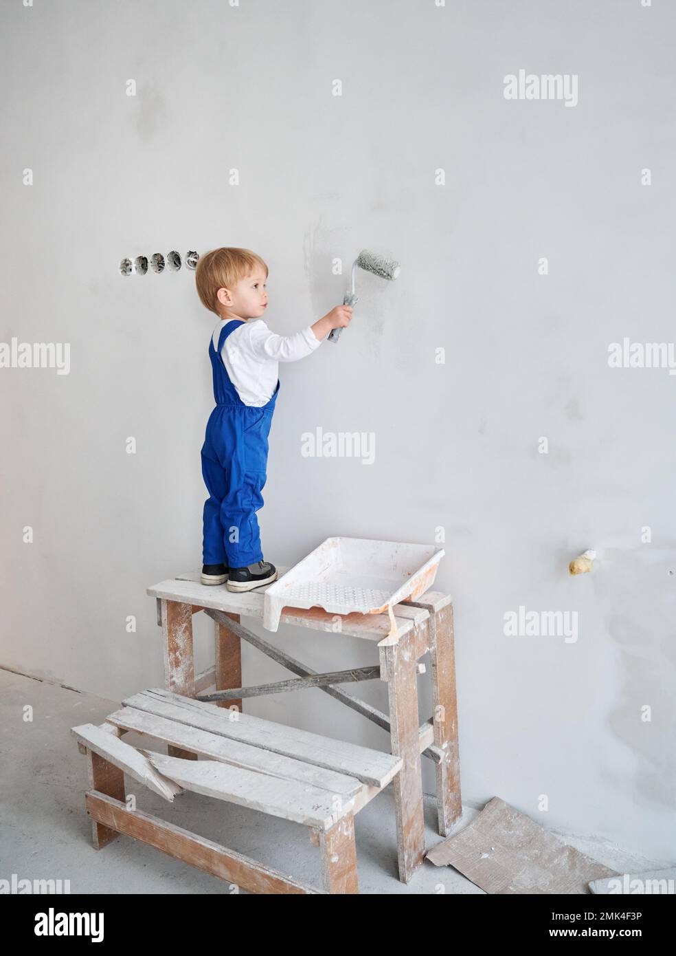 Little boy construction worker painting wall in apartment under ...