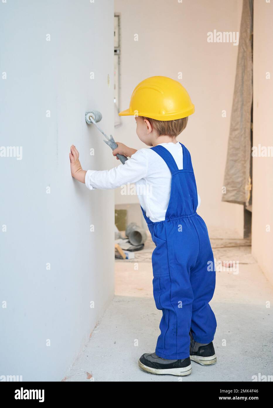 Full length of child construction worker painting wall in apartment ...