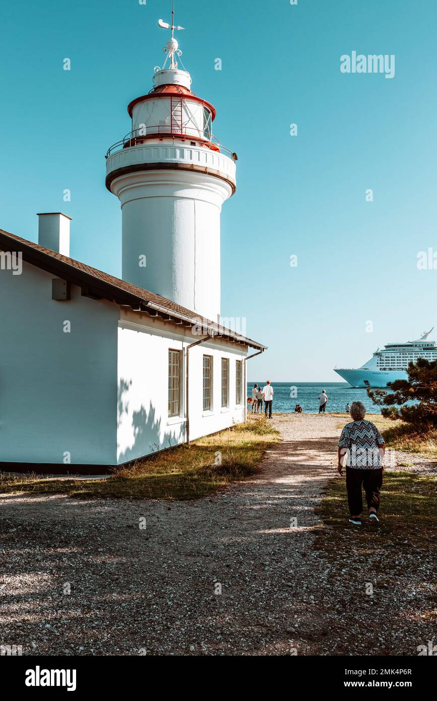 People watching a cruise ship passing Sletterhage Fyr lighthouse on the ...