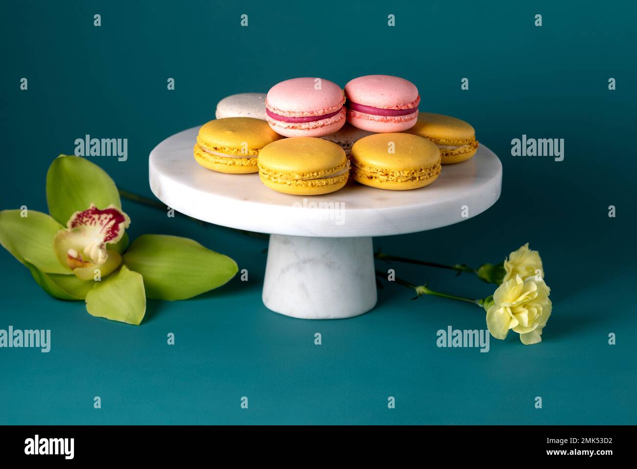 French macaron cakes on a marbel white cake stand against blue backdrop ...
