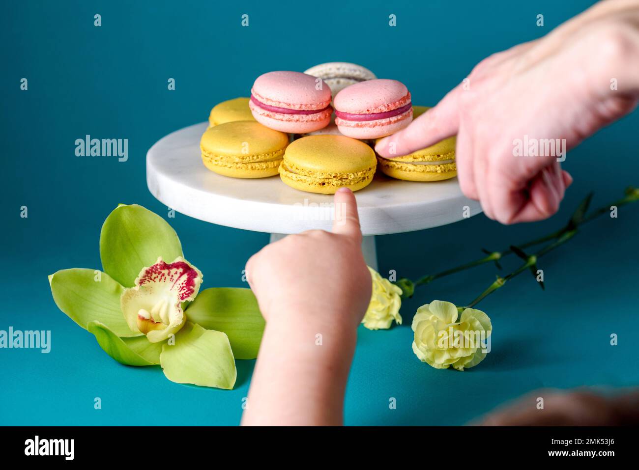 French macaron cakes on a cake stand against blue backdrop close up ...