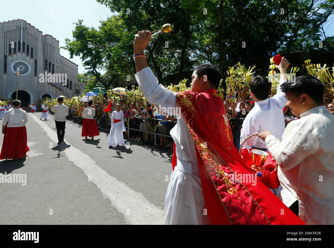 Catholic devotees wave their palm fronds as a Roman Catholic priest ...
