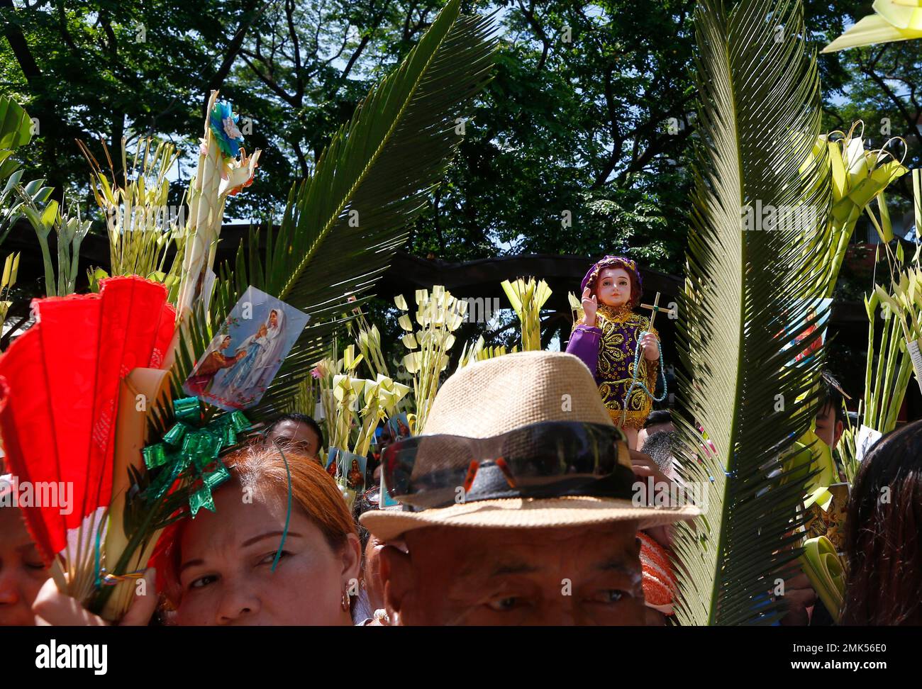 Catholic devotees wave their palm fronds and religious icons as a Roman ...