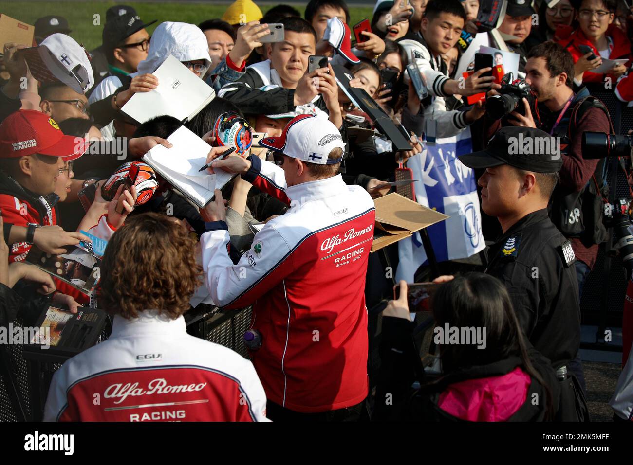 Alfa Romeo driver Kimi Raikkonen of Finland signs his autograph for ...