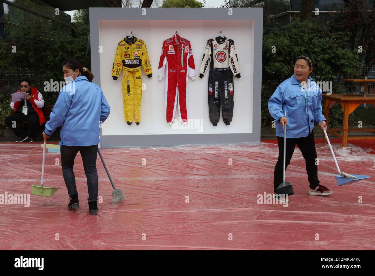 Cleaners work near a display of race suits as part of a promotion for ...
