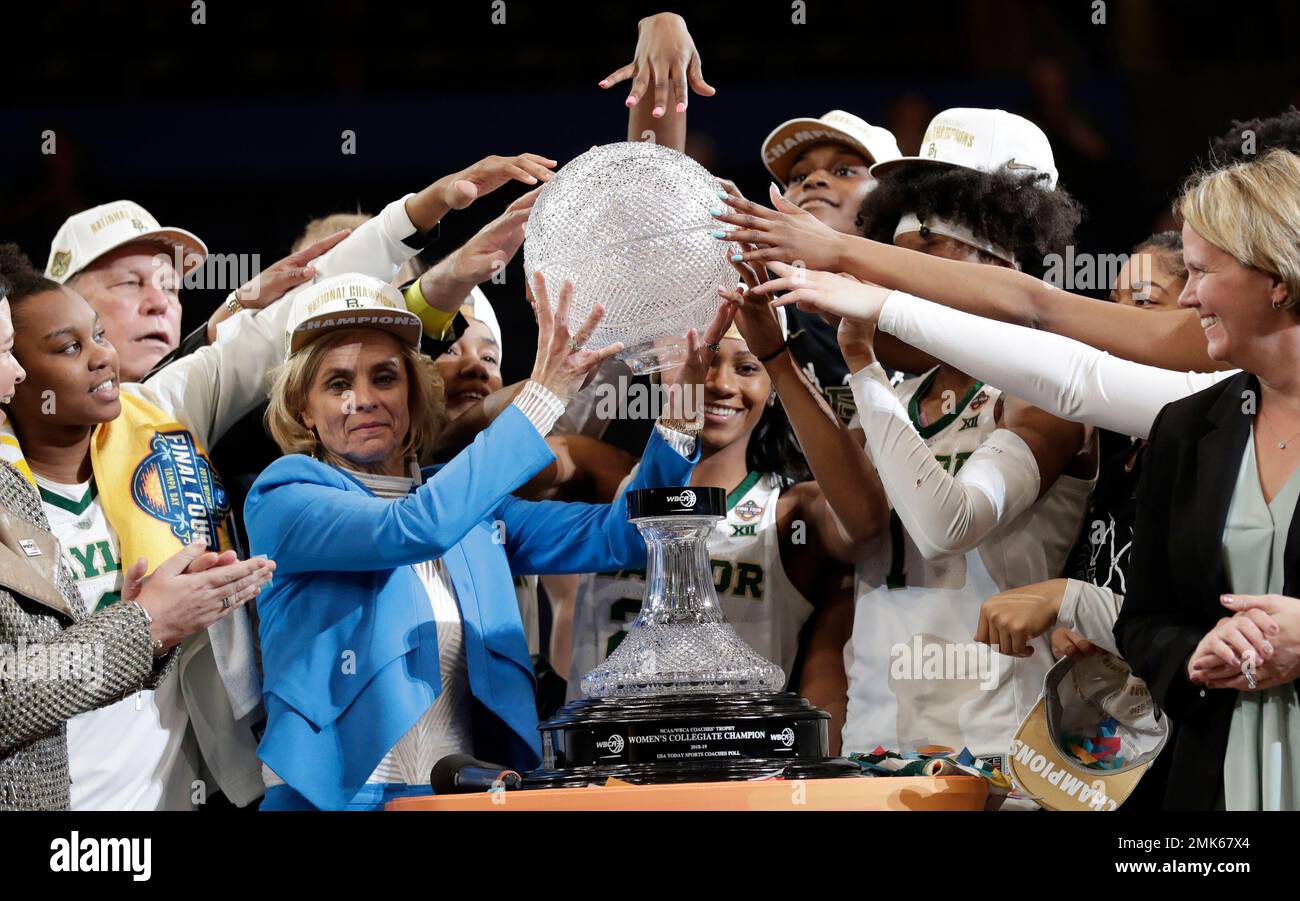 Baylor coach Kim Mulkey, in blue, and players raise part of the NCAA/WBCA coaches' trophy after ...
