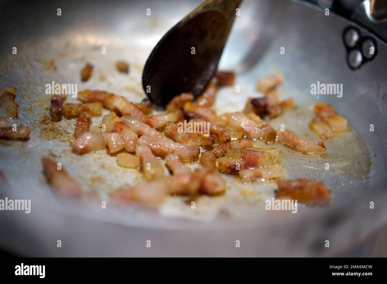 Pieces of guanciale (pork cheek) are sizzled in a pan during a cooking ...