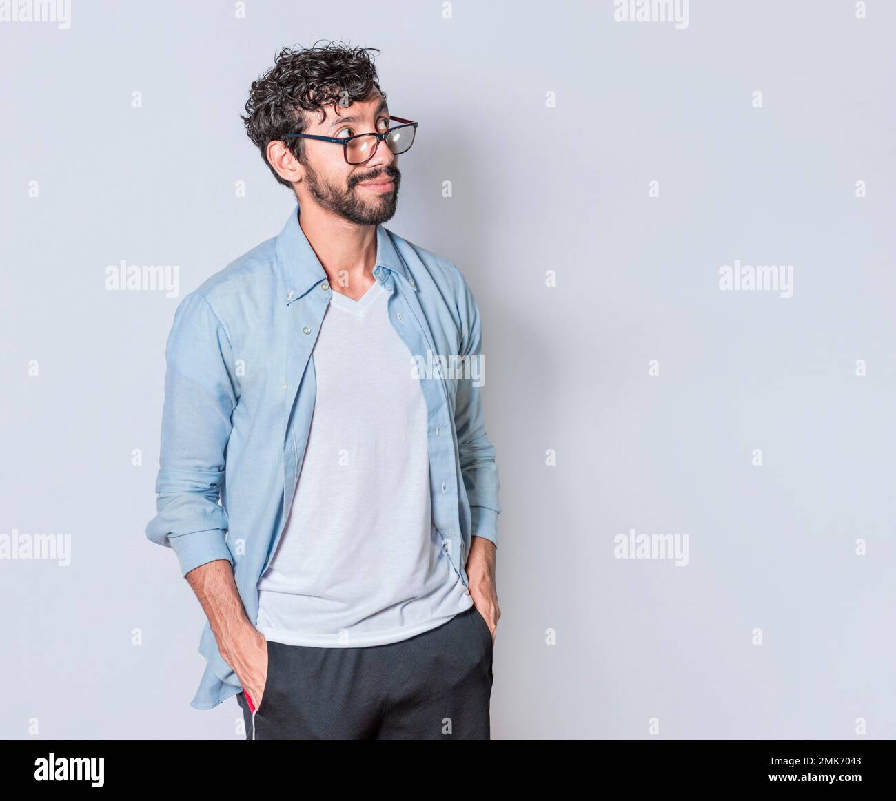 Young man wondering with hand in pocket over isolated background ...