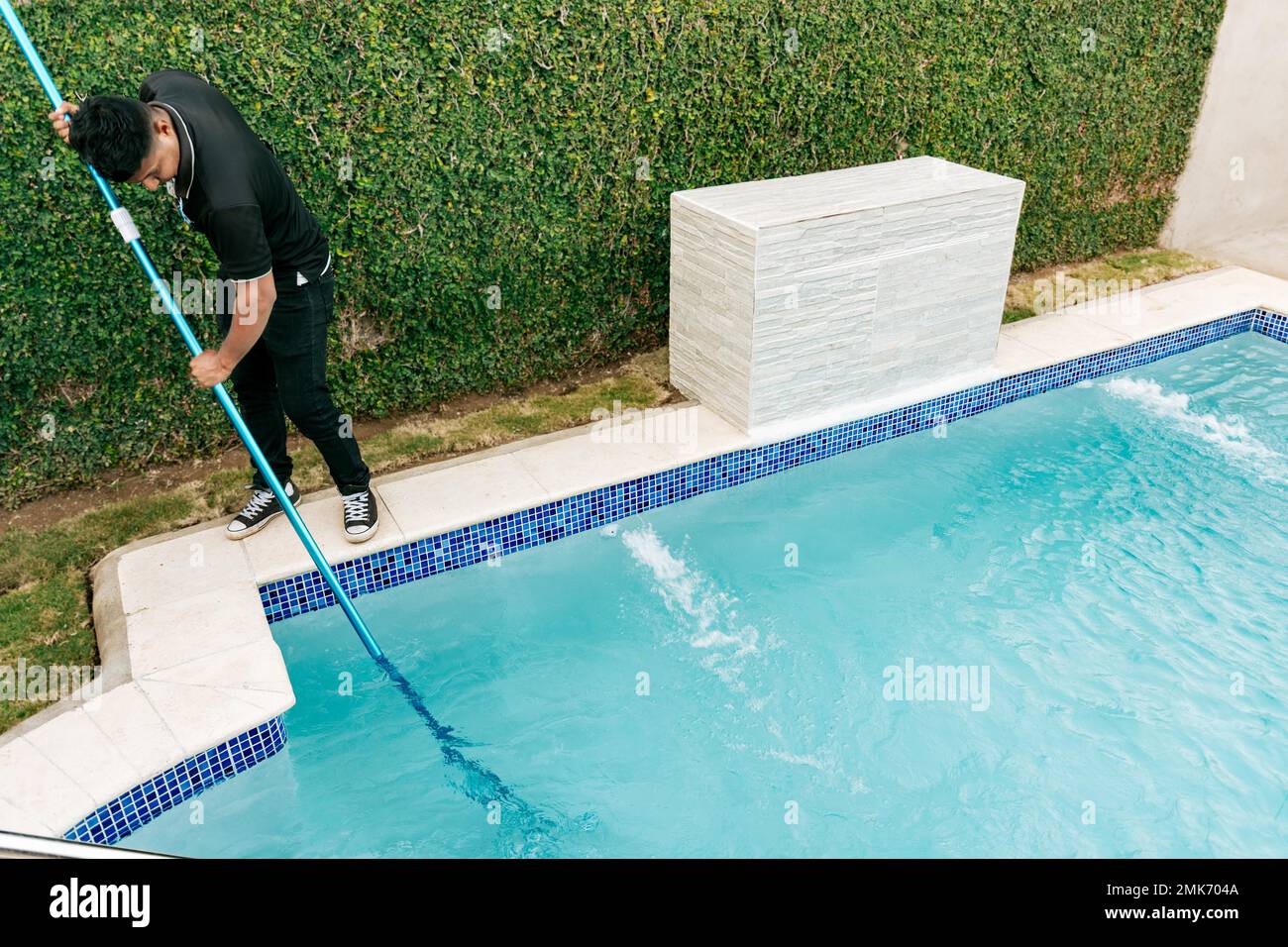 Maintenance person cleaning a swimming pool with skimmer, Worker ...