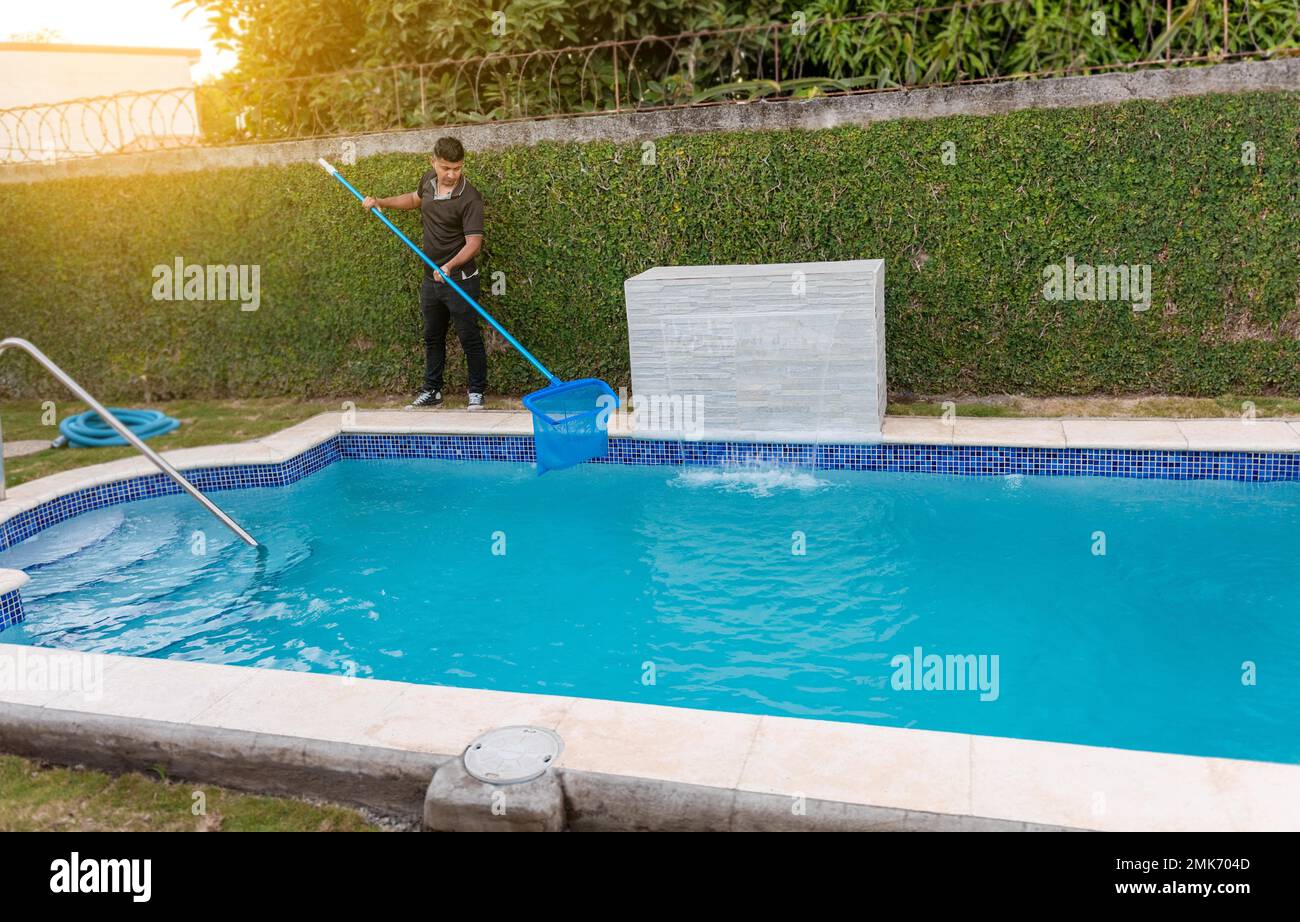 Maintenance person cleaning a swimming pool with skimmer, Worker ...
