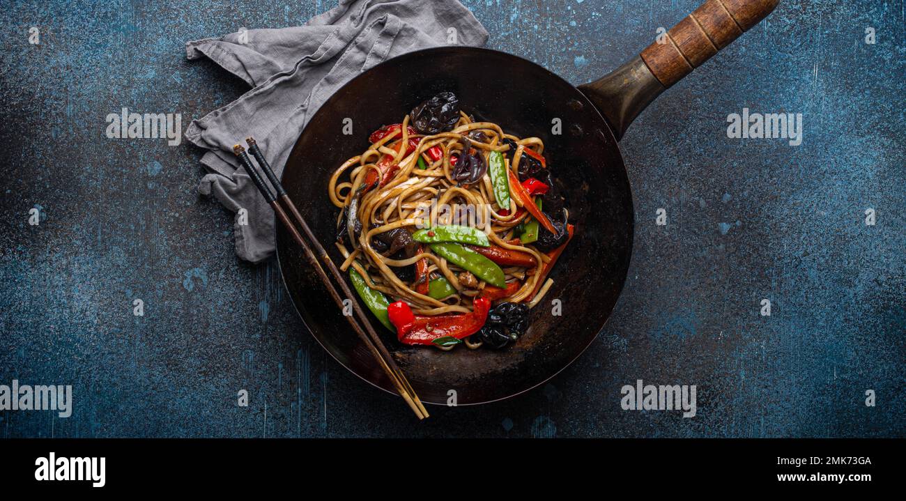 Asian dish stir fry udon noodles with vegetables and mushrooms in black ...