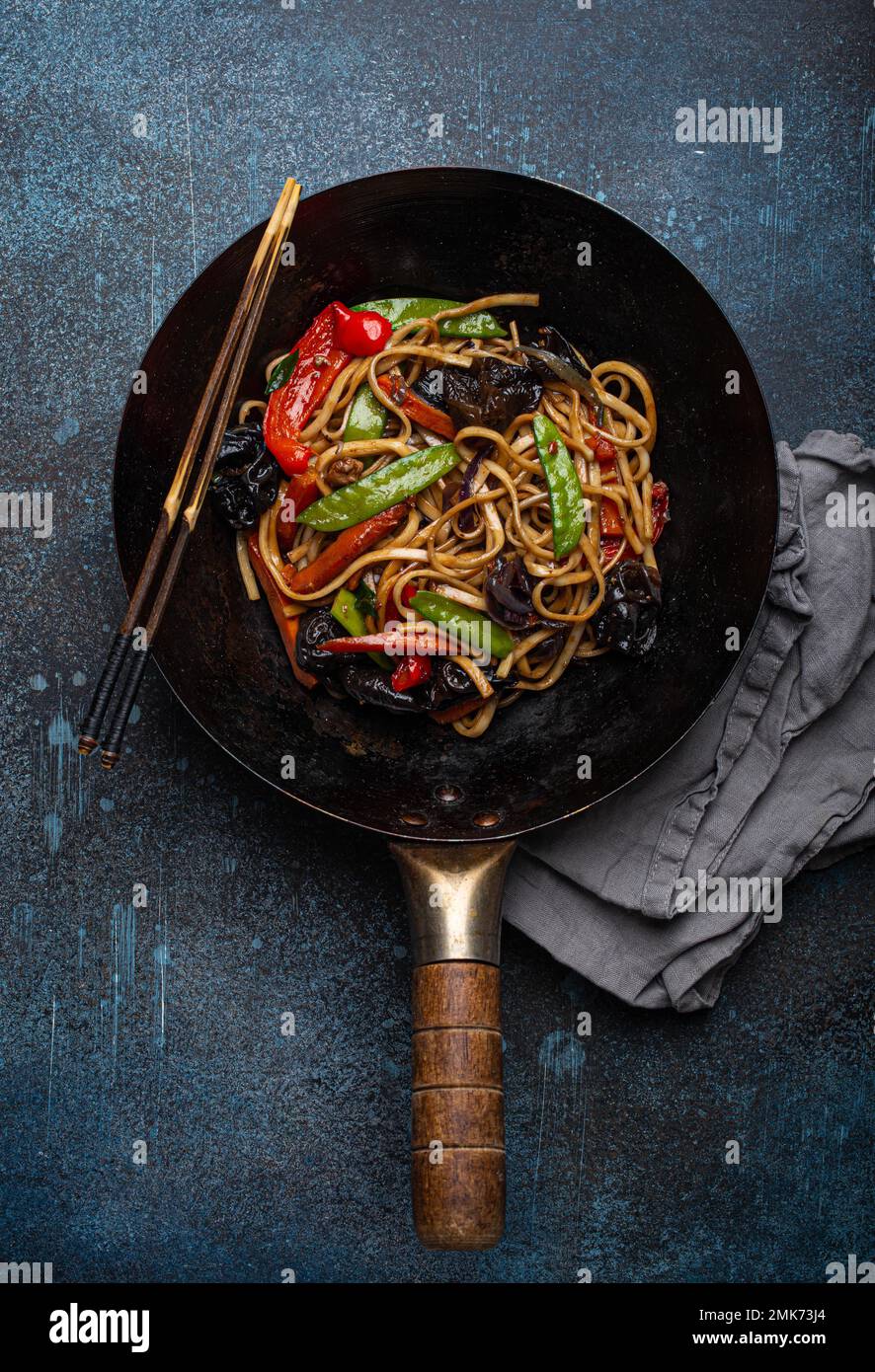 Asian dish stir fry udon noodles with vegetables and mushrooms in black ...