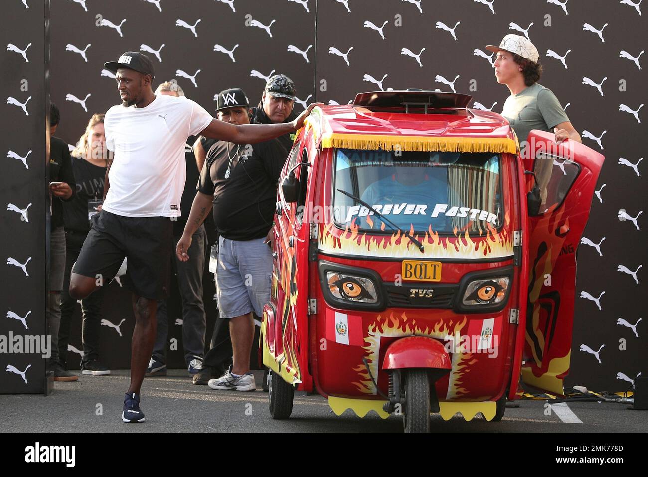 Jamaican sprinter Usain Bolt warms up next to his opponent, a mototaxi ...