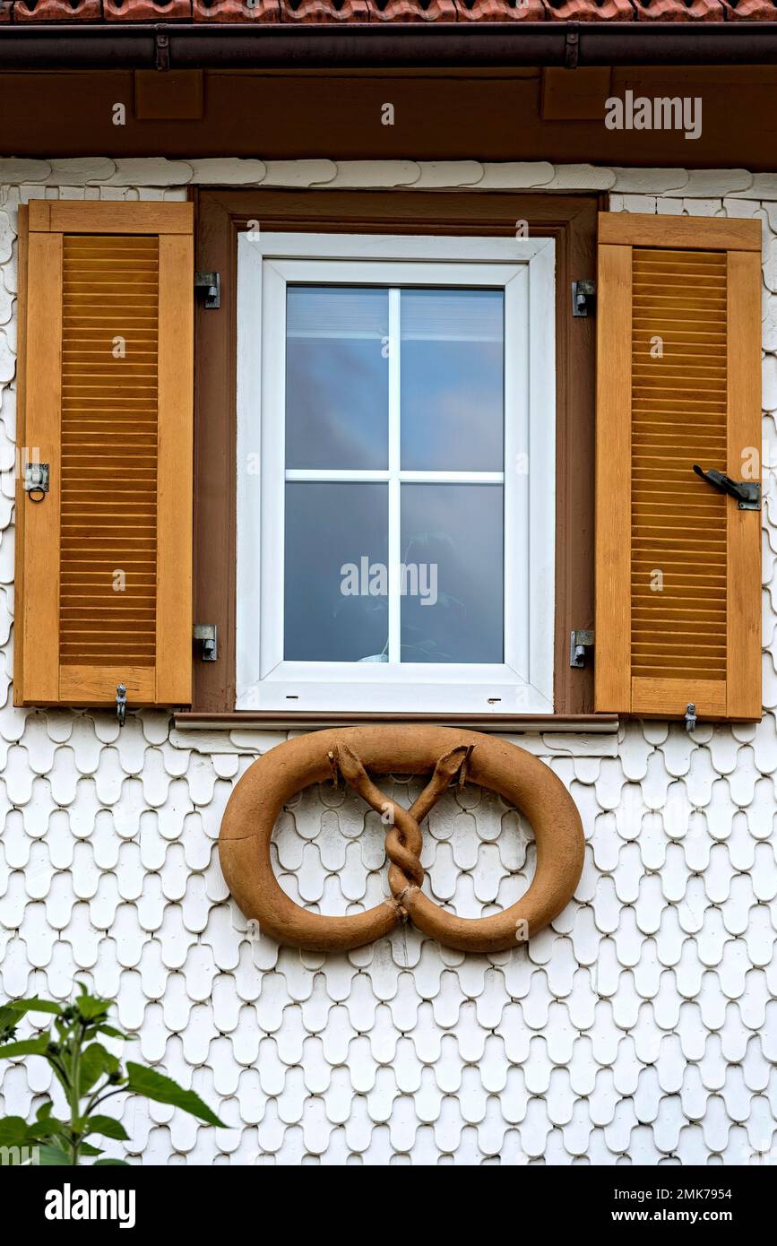 Residential house with wooden shingles as facade, large pretzel under ...