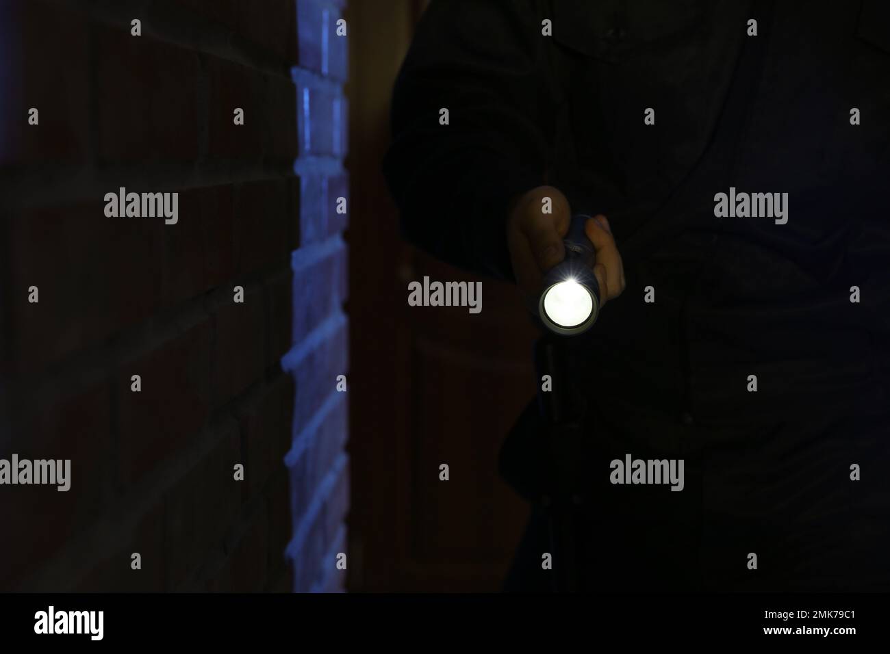 Male security guard with flashlight near brick wall in darkness Stock ...