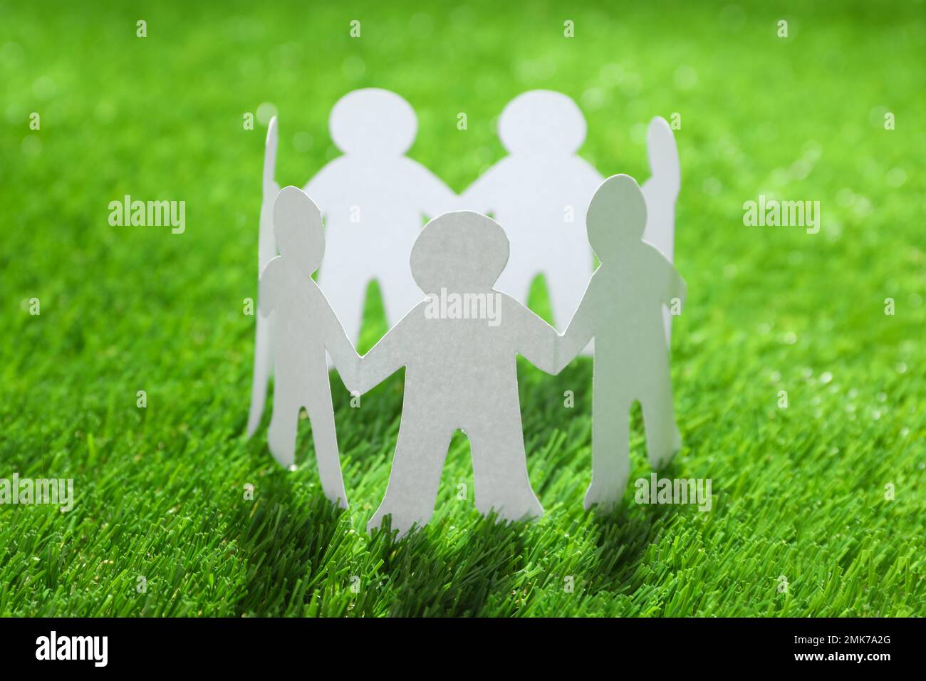 Paper people chain making circle on green grass. Unity concept Stock ...