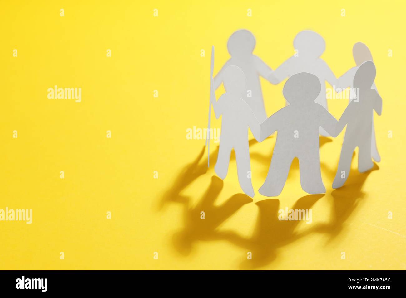 Paper people chain making circle on yellow background, space for text ...