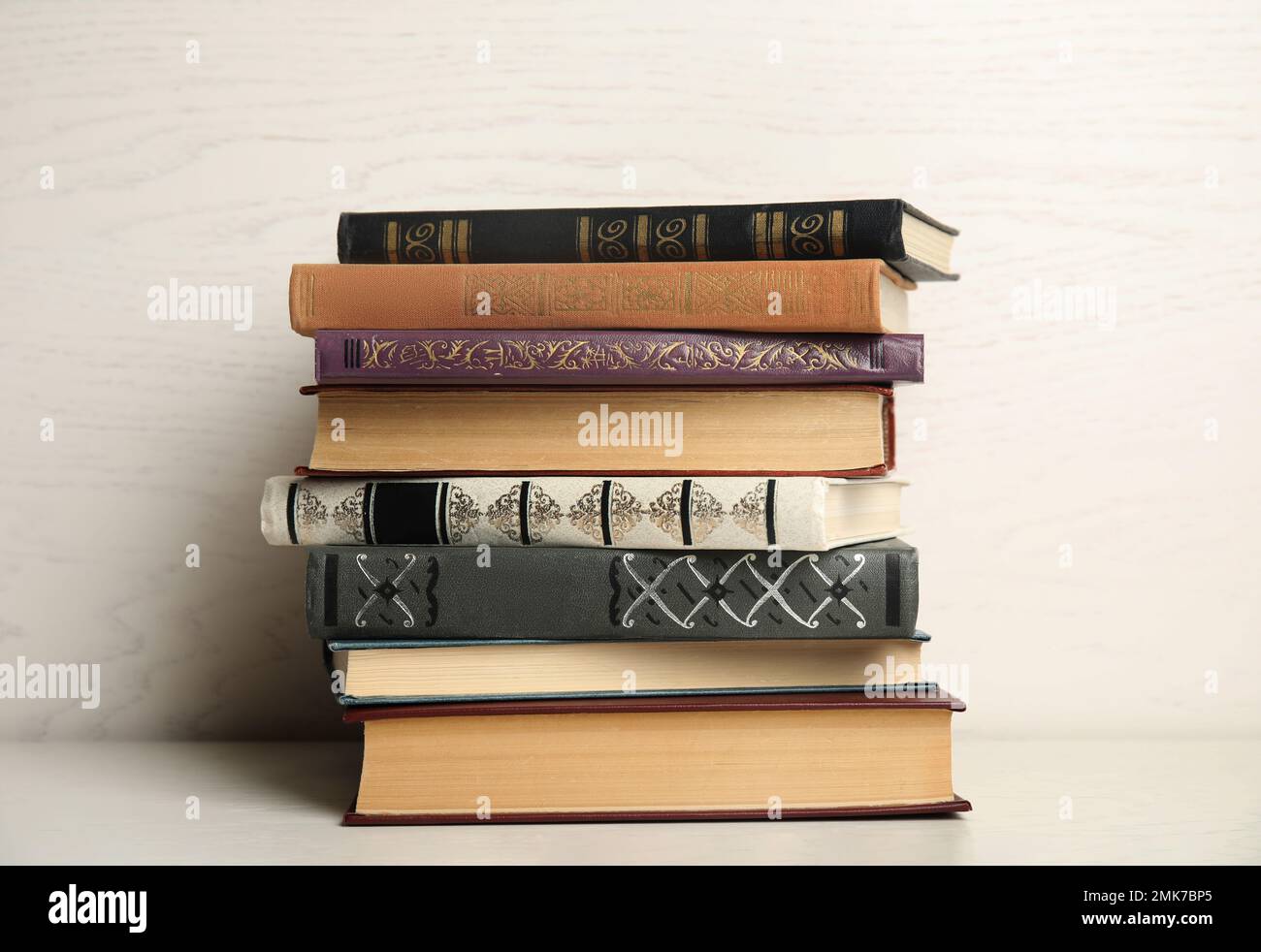 Collection of different books on table against white wooden background ...