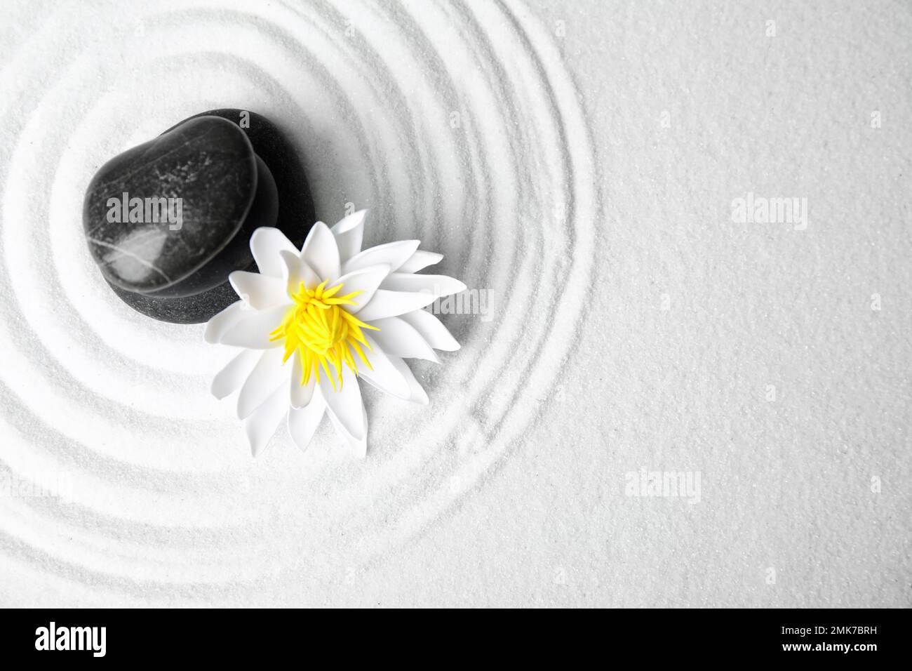 Zen garden. Beautiful lotus flower and stones on white sand, flat lay ...