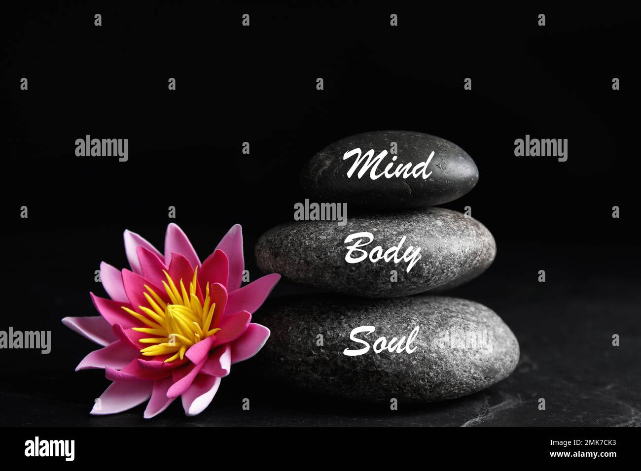 Stones with words Mind, Body, Soul and lotus flower on black background ...
