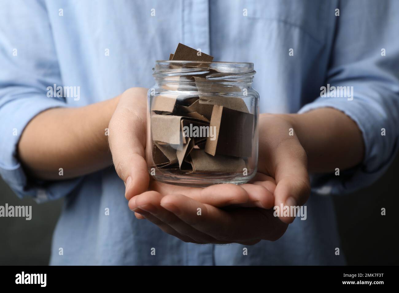 Woman holding glass jar with paper pieces, closeup on hands Stock Photo ...