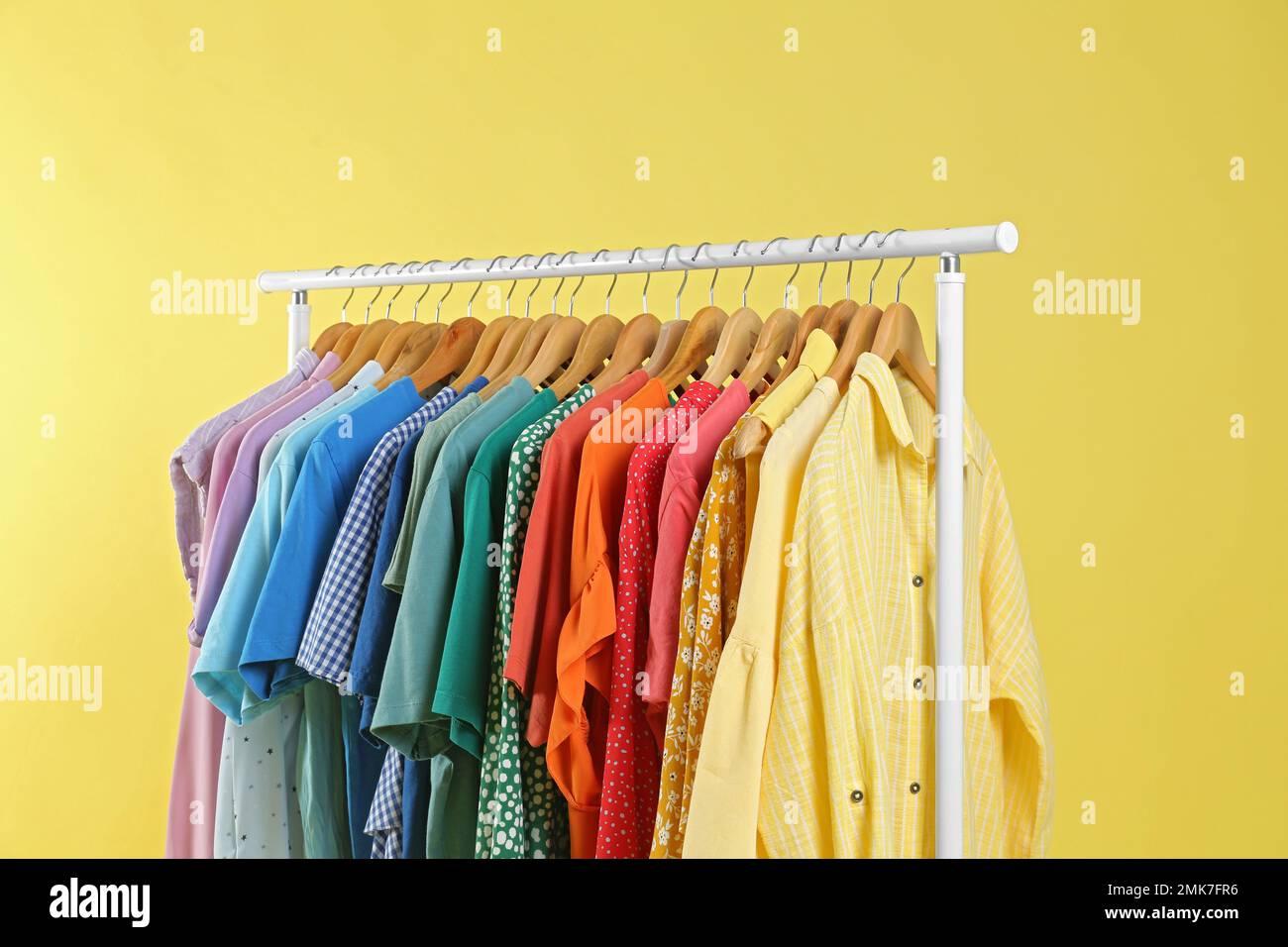 Bright clothes hanging on rack against yellow background. Rainbow ...