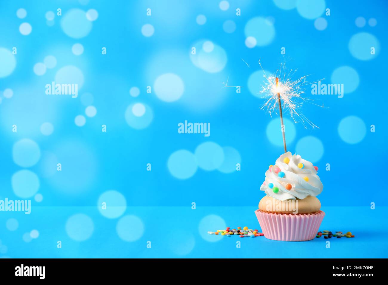 Birthday cupcake with sparkler on light blue background, space for text ...