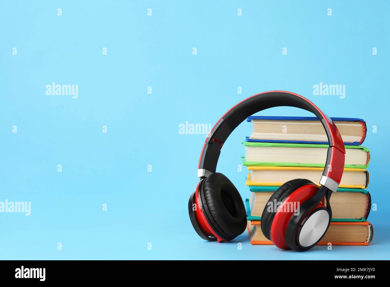 Books and modern headphones on light blue background. Space for text ...