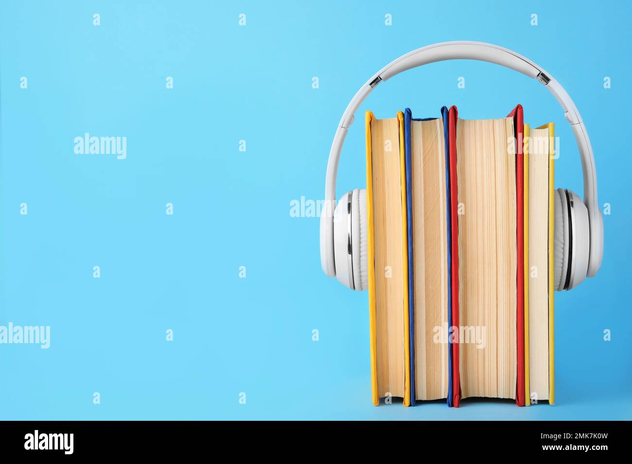 Books and modern headphones on light blue background. Space for text ...