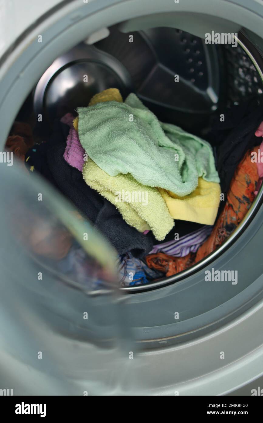 man putting shirt into washing machine Stock Photo - Alamy