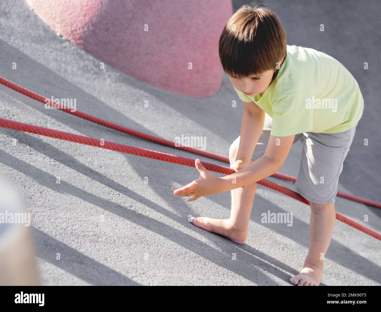 Boy climbes up a concrete slope of modern children's sports and ...