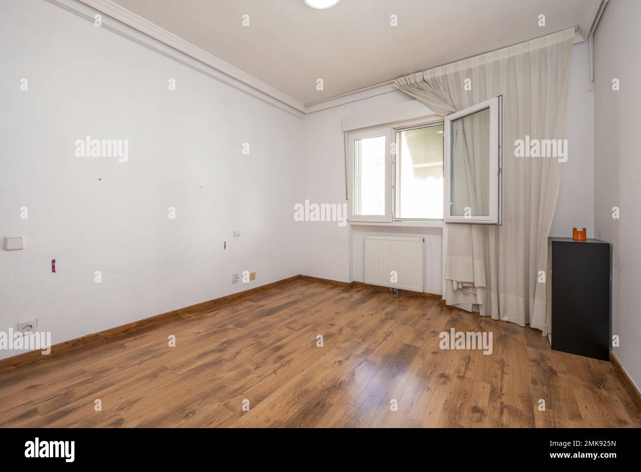 Empty room with wooden floor, plaster moldings on the ceiling, aluminum ...