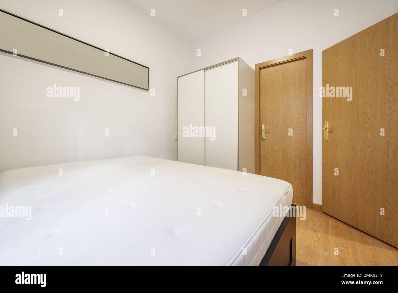 Bedroom with double bed with mattress without bedding, wardrobe with ...