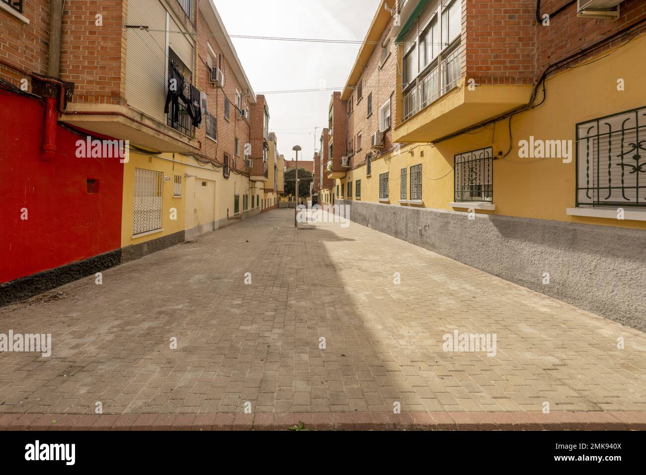 Pedestrian street between buildings with brick facades and metal gates ...