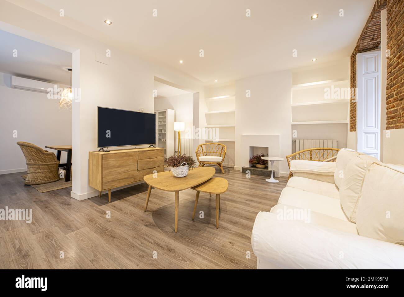 Living room with doorless access to a dining room with light wood ...