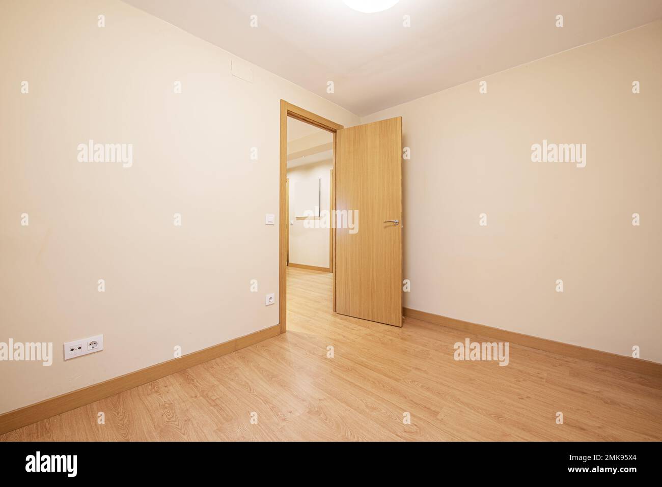 Empty room with floating oak flooring with a door of the same material ...