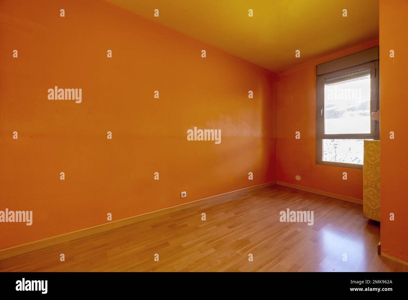 Small empty room with brown wooden floor and deep orange painted walls ...