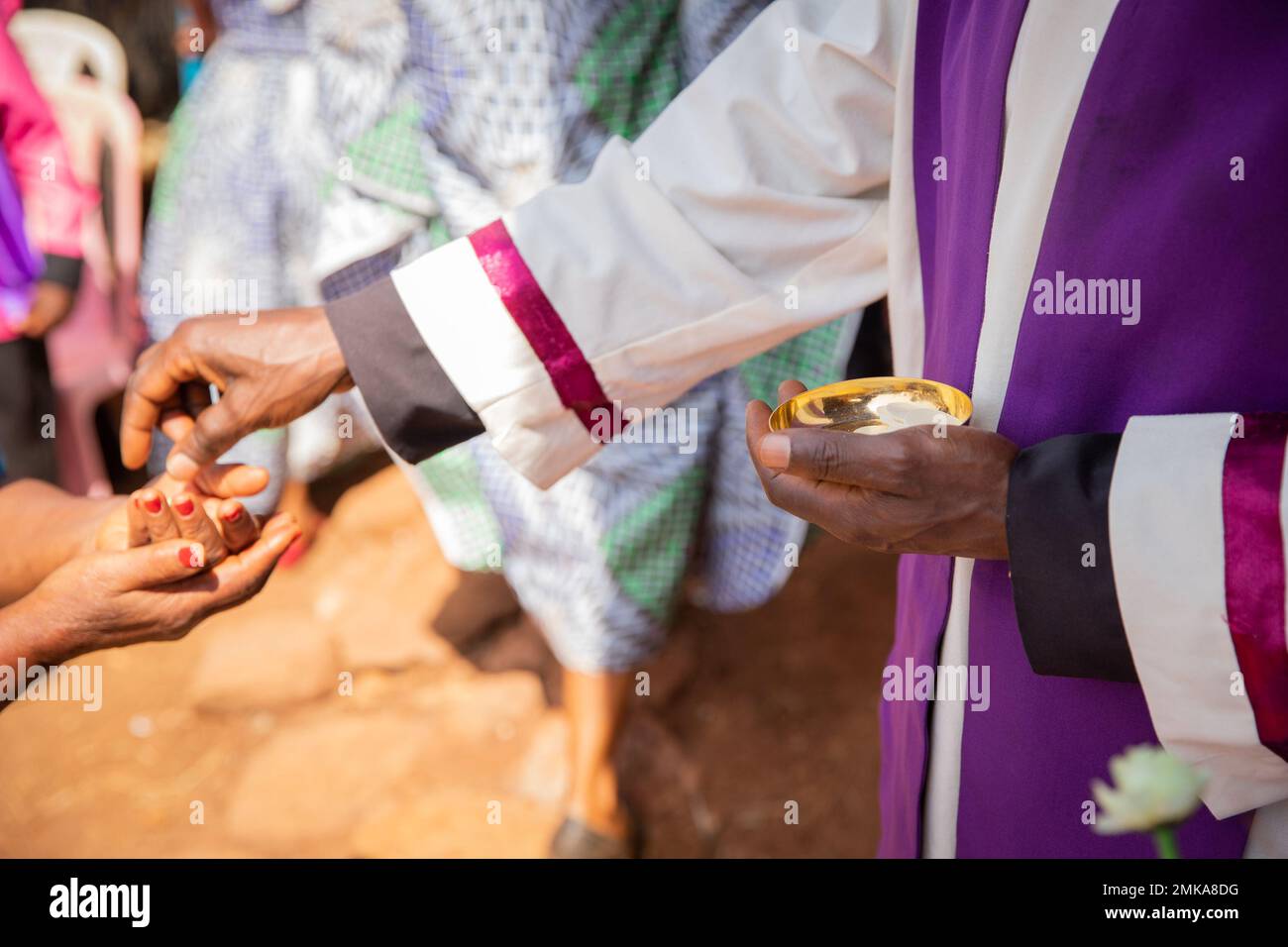 An African priest gives sacramental bread to a believer, focus on the ...
