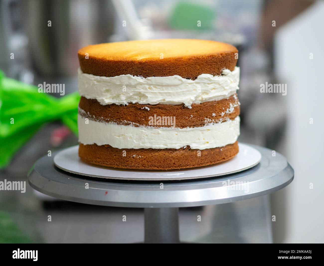 chef pastry designer confectioning a frosted 3 floor layered cake ...