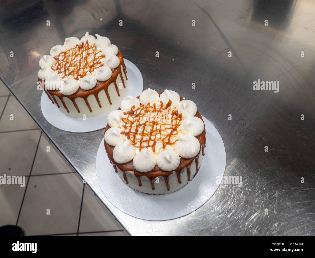 chef pastry baker preparing salty caramel frosted dripping white cakes ...
