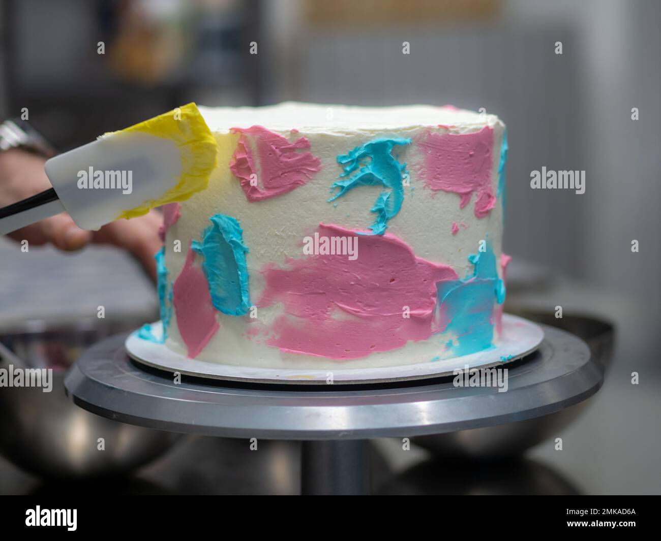 chef pastry designer confectioning a frosted 3 floor layered cake ...