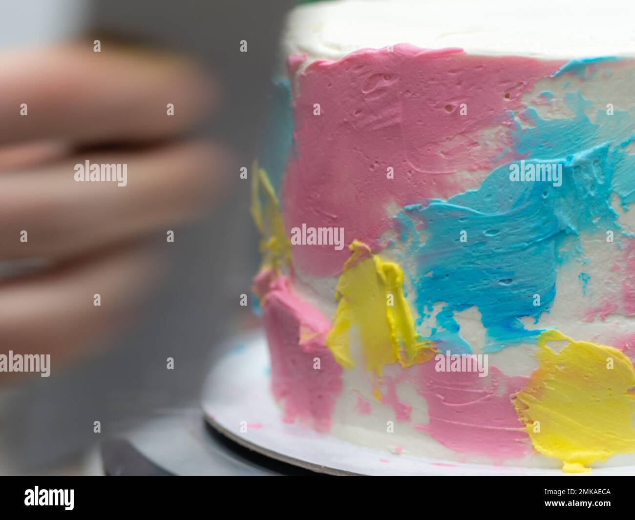 chef pastry designer confectioning a frosted 3 floor layered cake ...