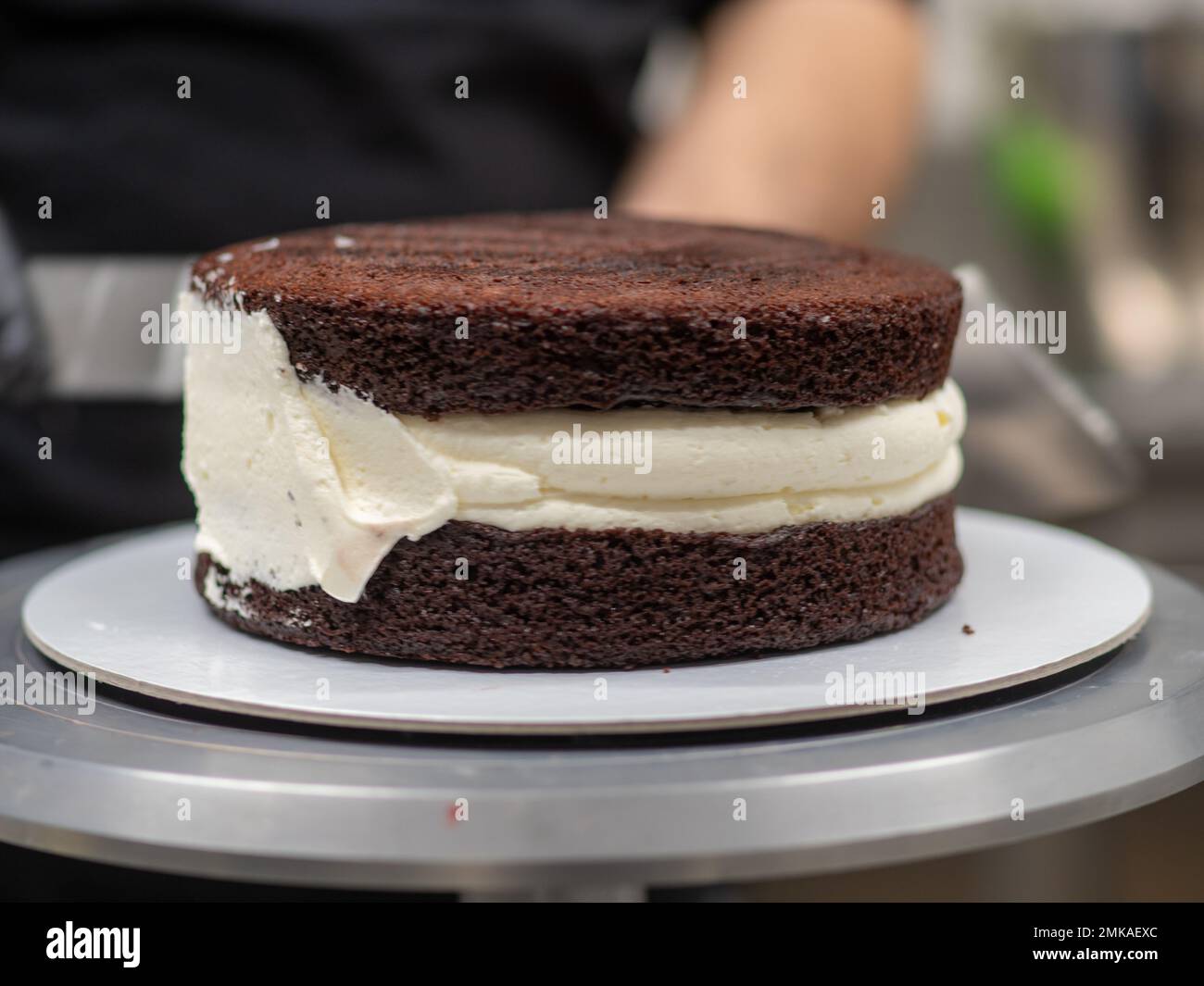 chef pastry designer confectioning a frosted 3 floor layered cake ...