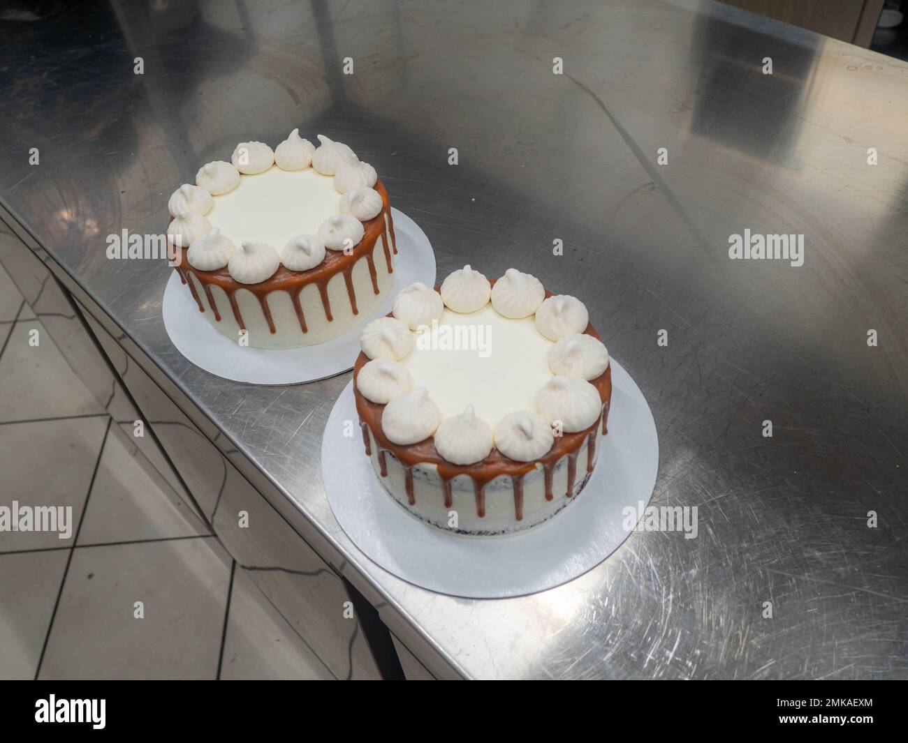 chef pastry baker preparing salty caramel frosted dripping white cakes ...