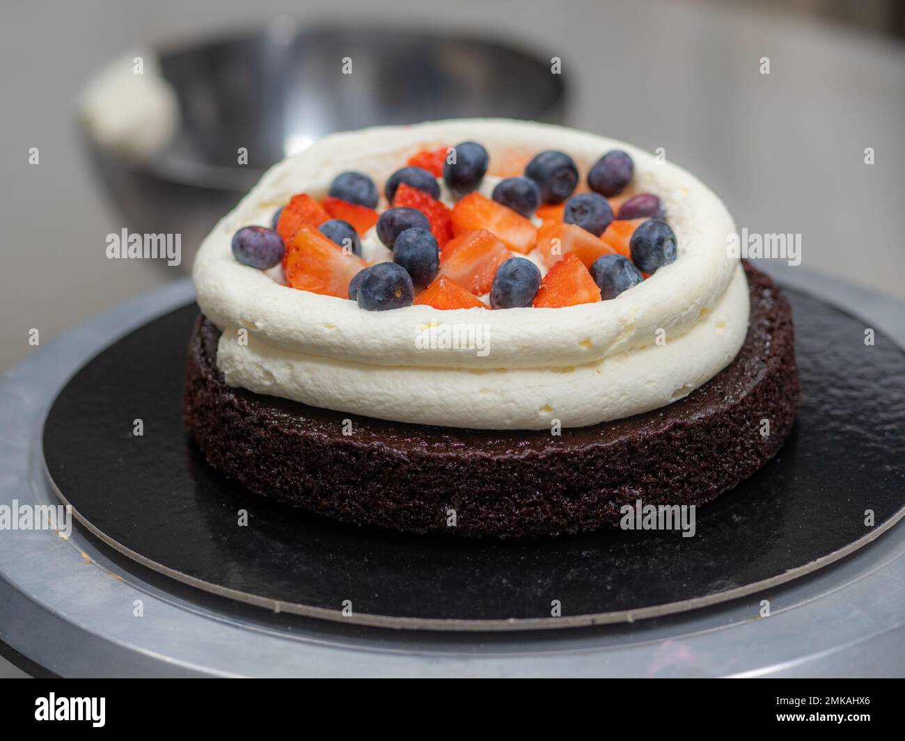 chef pastry designer confectioning a frosted 3 floor layered cake ...