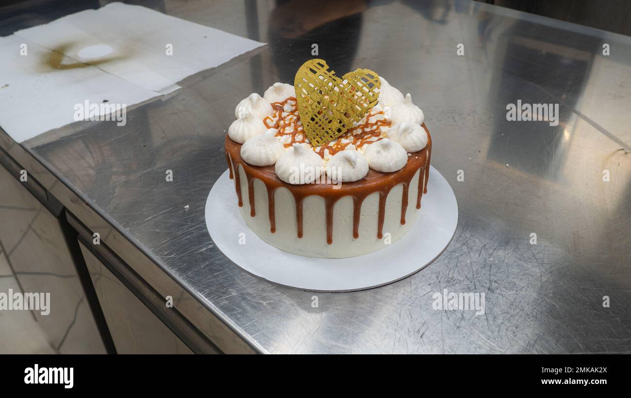 chef pastry baker finishing salty caramel frosted dripping cakes with ...