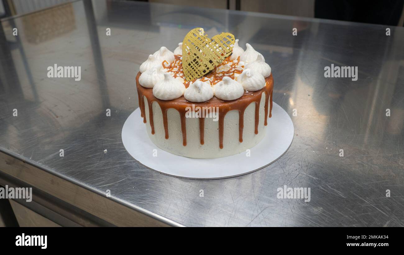 chef pastry baker finishing salty caramel frosted dripping cakes with ...